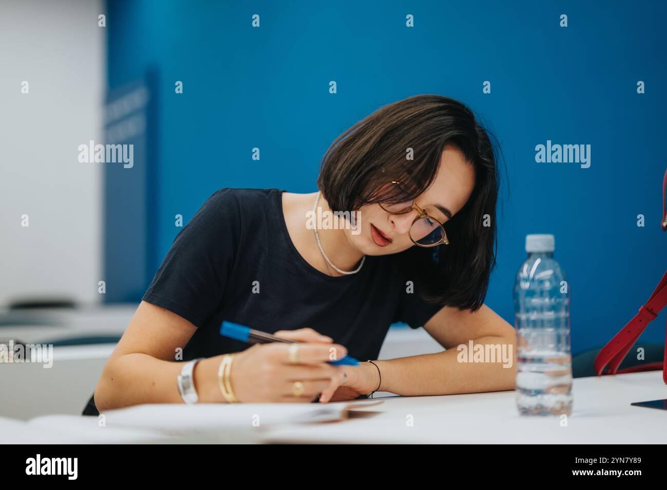 Focused student writing notes during class in blue classroom Stock ...