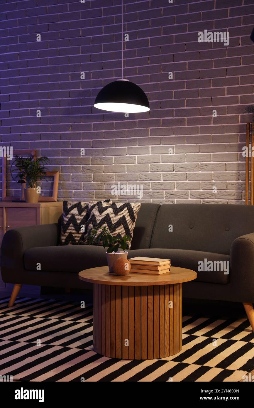 Interior of living room with cozy sofa, coffee table and glowing lamps ...