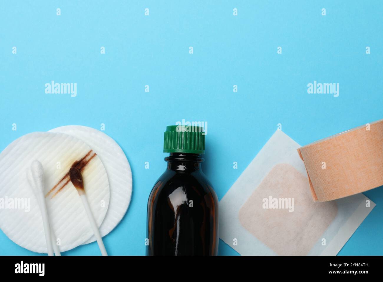 Topical iodine and other first aid kit components on light blue ...