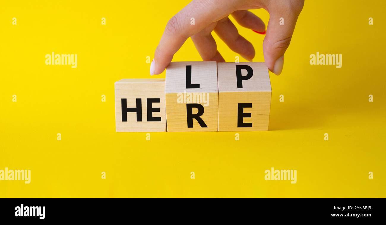 Help is here symbol. Businessman hand Turns cube and changes word Here ...