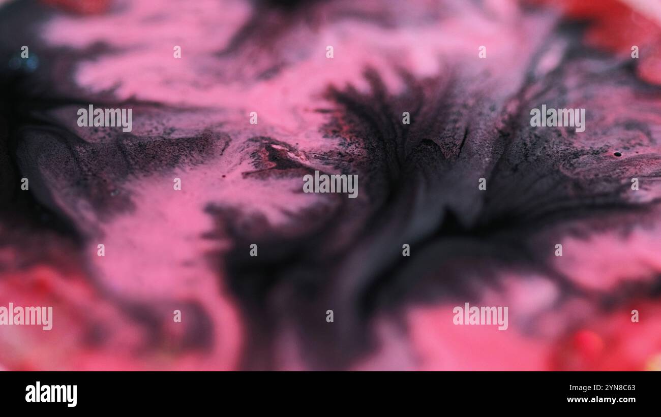 Ink blot. Acrylic fluid mix. Defocused pink red black color paint ...