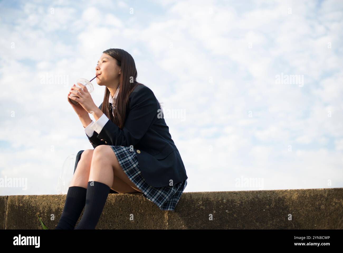 Schoolgirl in school uniform drinking something in a cup Stock Photo ...