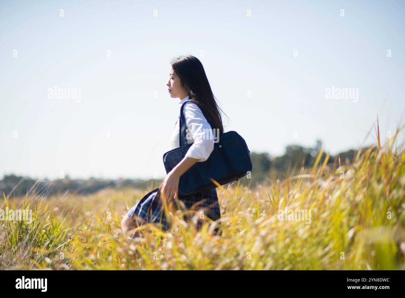 High school girl in school uniform walking on grassland Stock Photo - Alamy