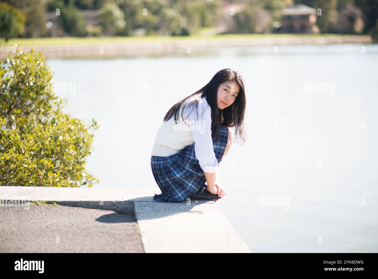 Schoolgirl in school uniform sitting by the water Stock Photo - Alamy