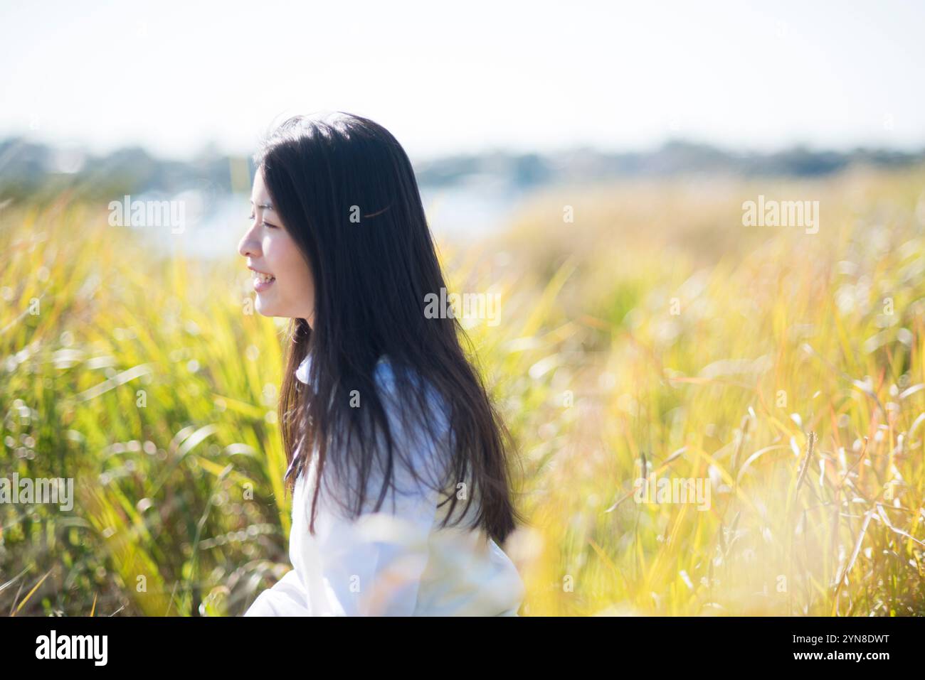 Schoolgirl in school uniform sitting on grassland laughing Stock Photo ...