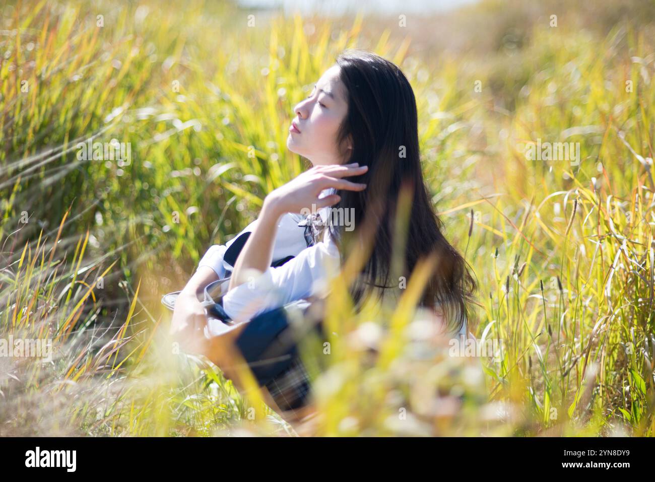 Schoolgirl in school uniform sitting in meadow Stock Photo - Alamy