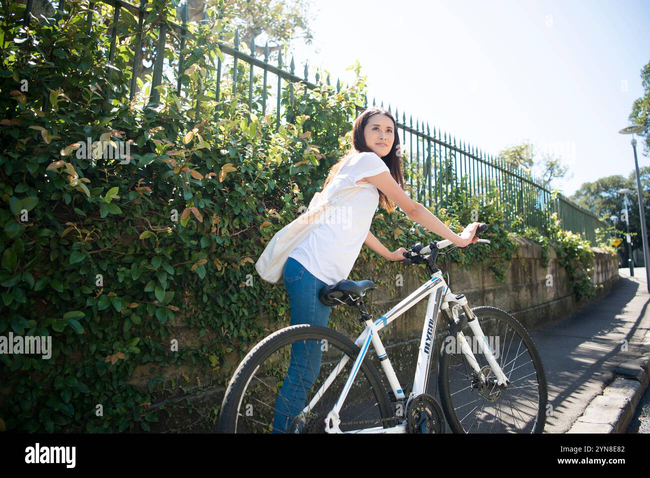 Woman pulling a bicycle and looking back Stock Photo - Alamy