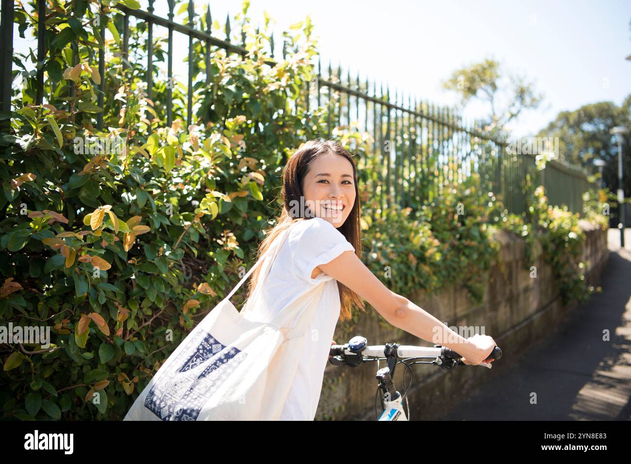 Woman pulling a bicycle and looking back Stock Photo - Alamy