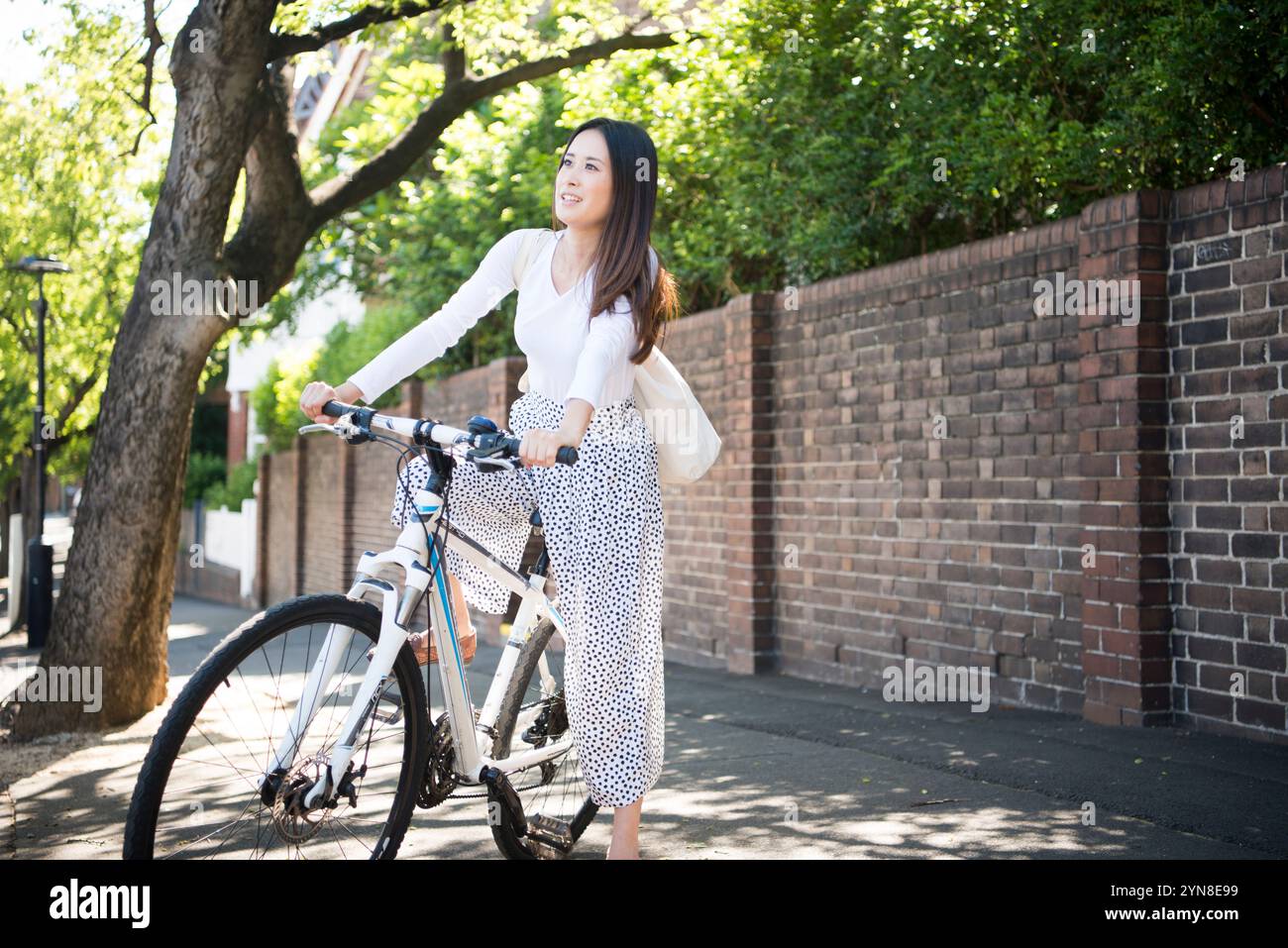 Woman pulling a bicycle Stock Photo - Alamy