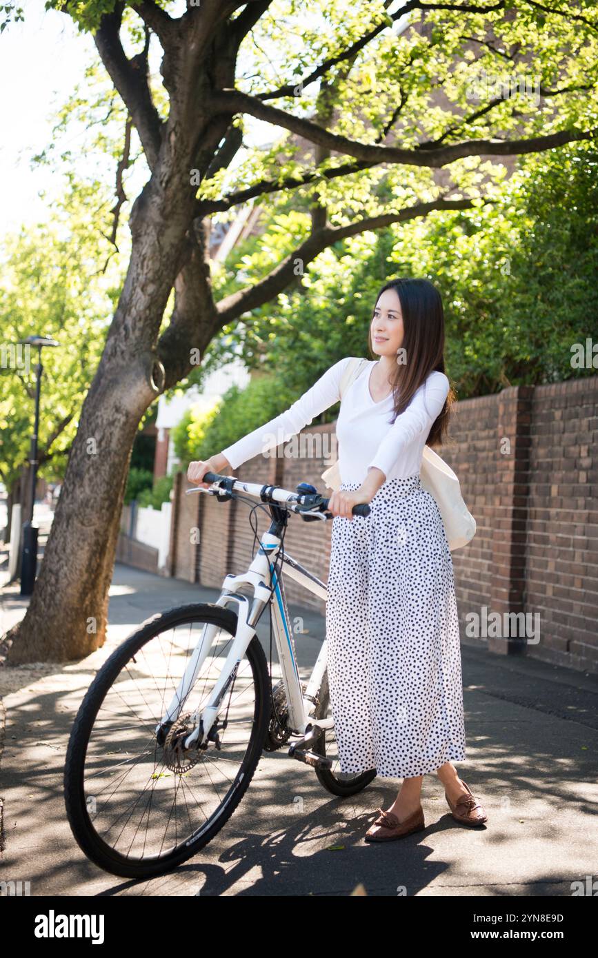 Woman pulling a bicycle Stock Photo - Alamy