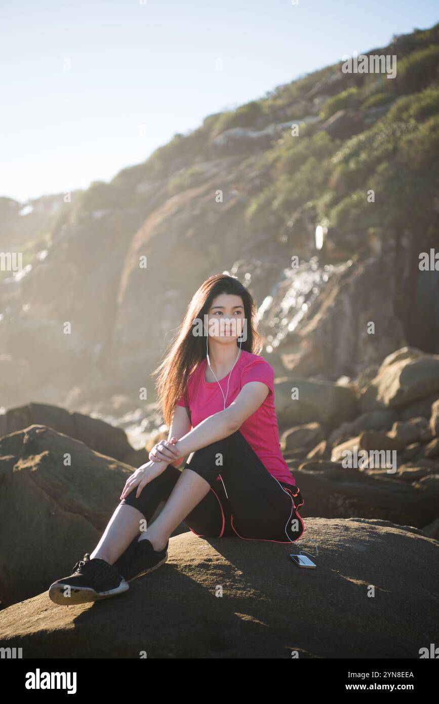 Woman sitting on rock in training wear Stock Photo - Alamy