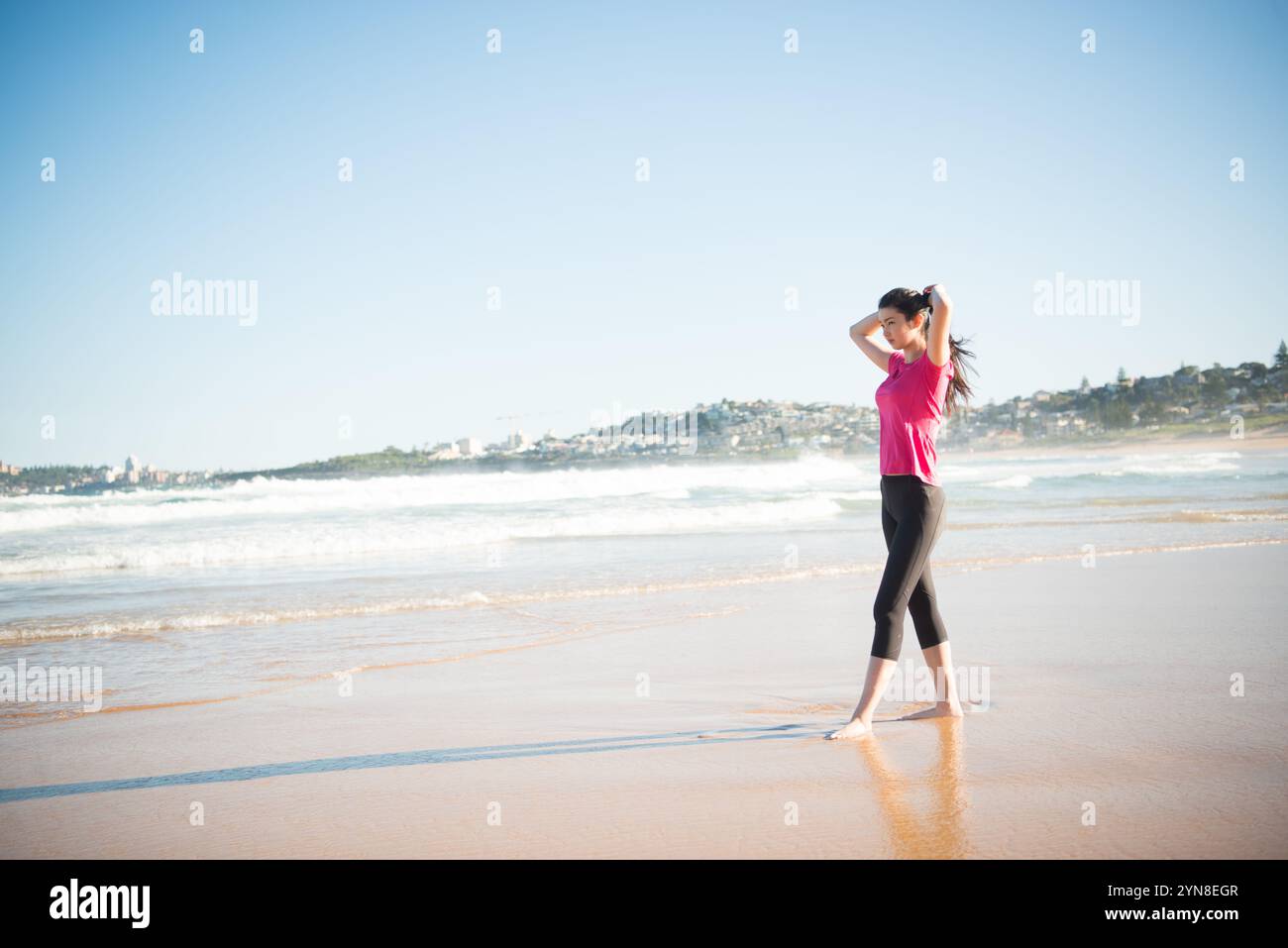 Woman walking on beach in training wear Stock Photo - Alamy