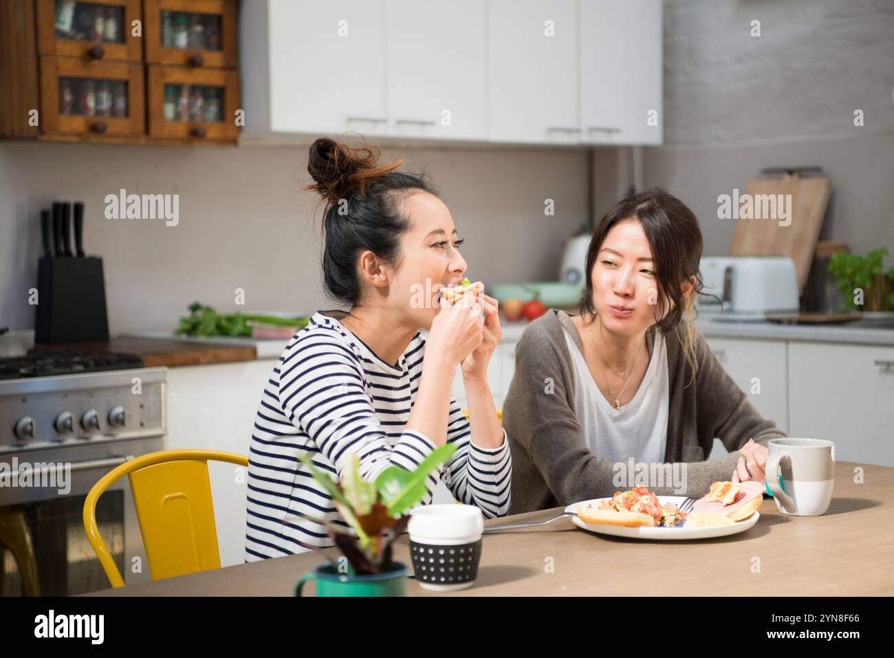 Two women eating rice in the kitchen Stock Photo - Alamy