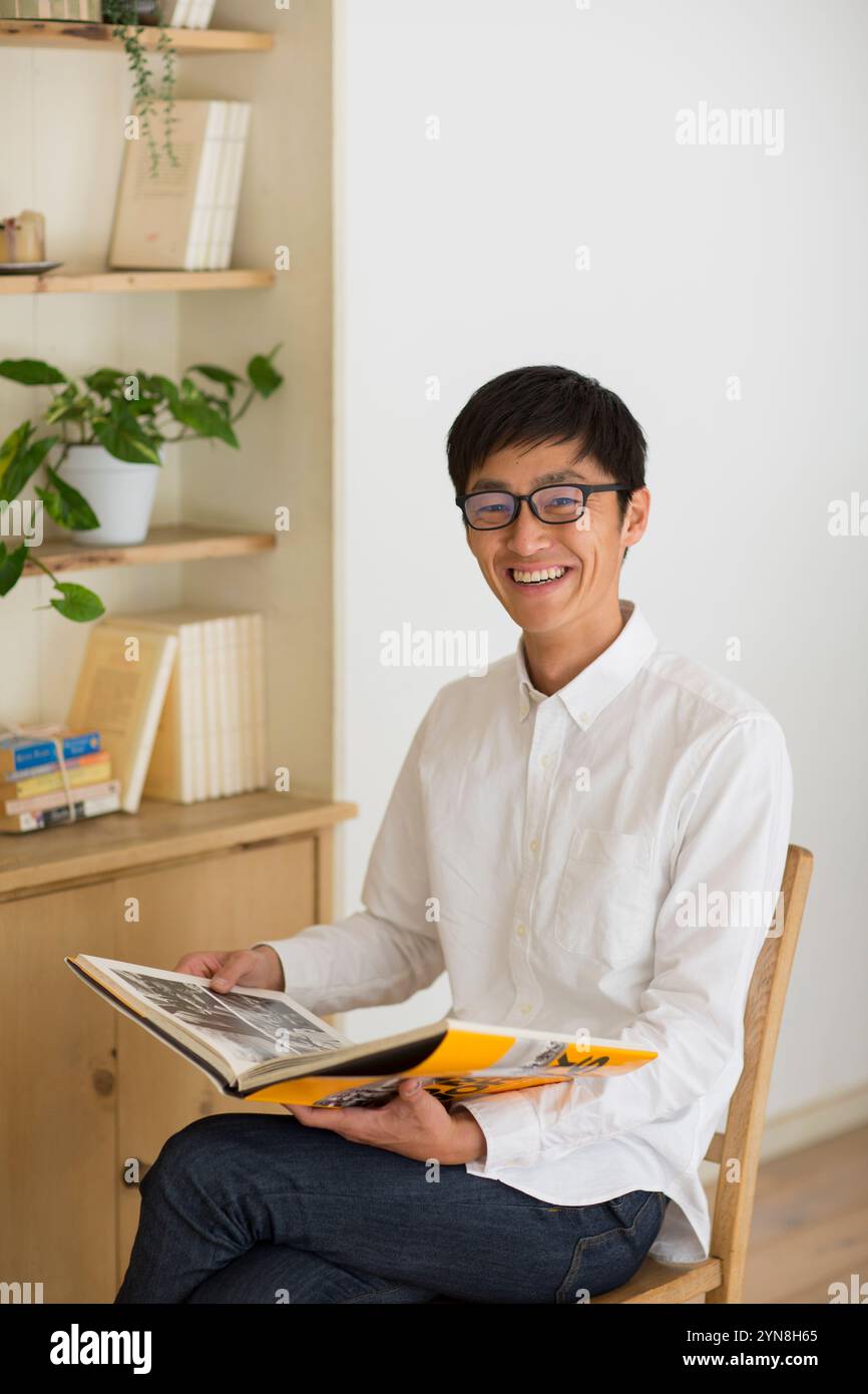 Smiling man reading book indoors Stock Photo - Alamy