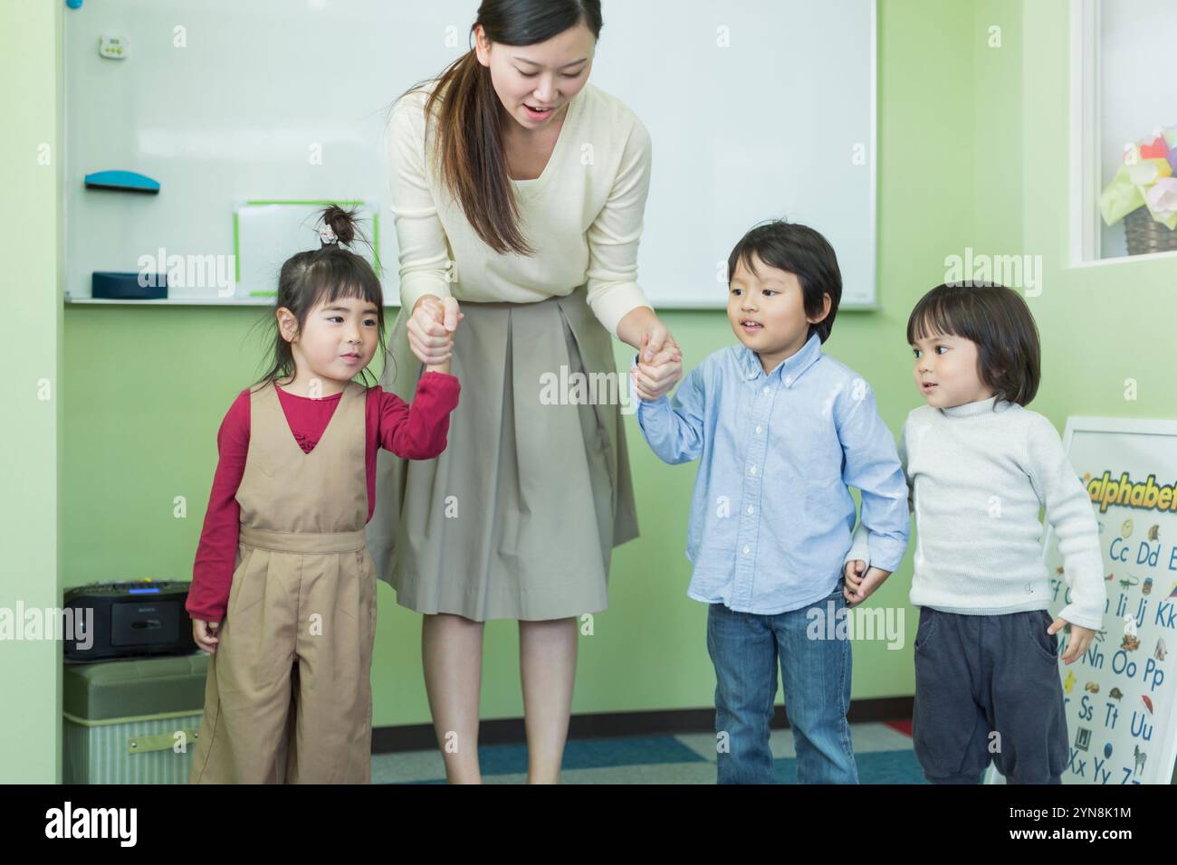 Teachers and children holding hands in a classroom Stock Photo - Alamy