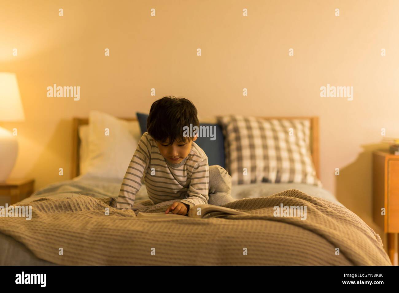 Boy reading book in bed Stock Photo - Alamy
