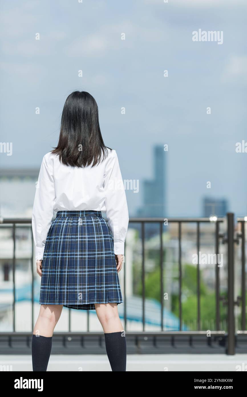 Rear view of female student standing on rooftop Stock Photo - Alamy