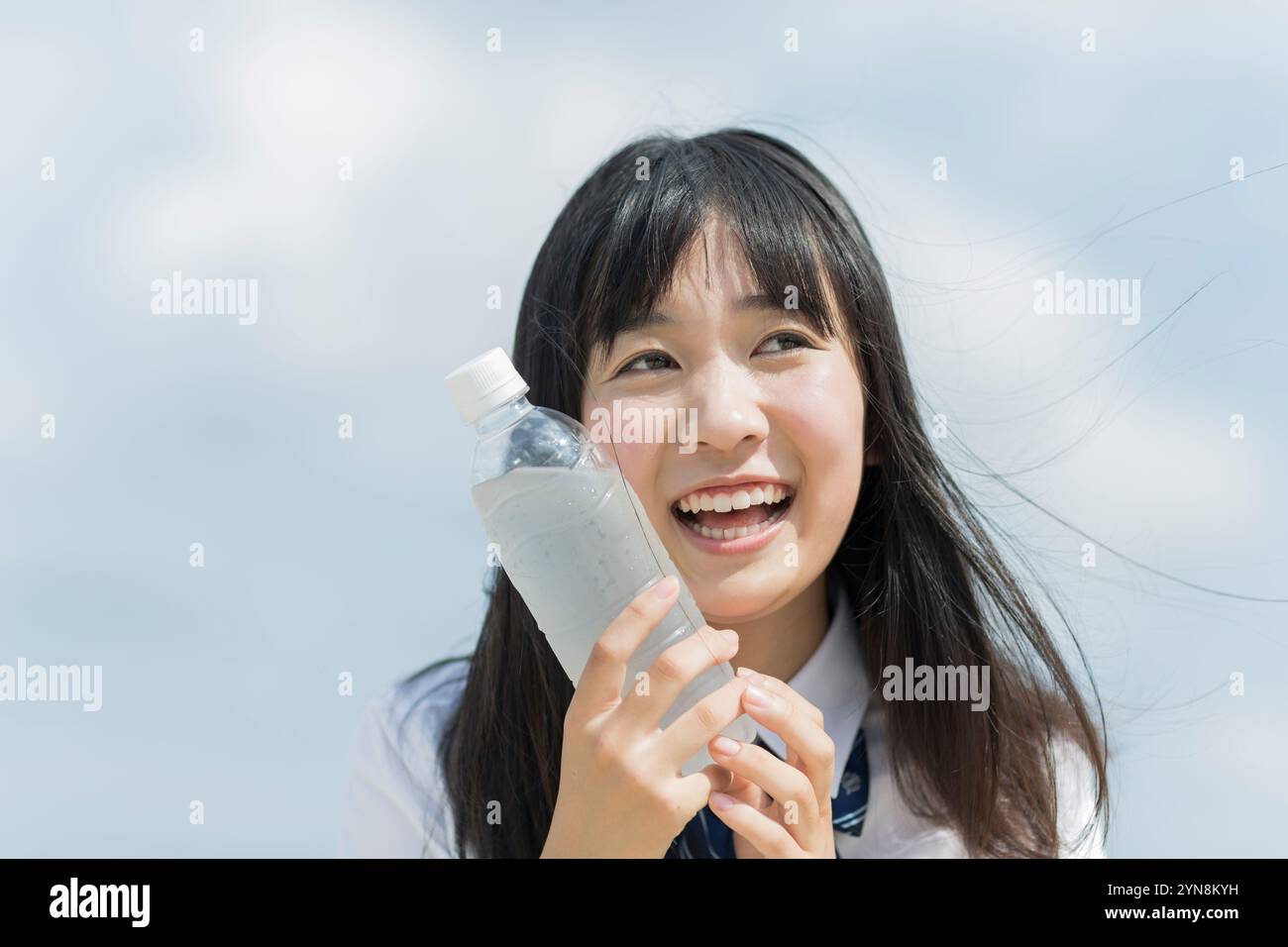 Female student holding a plastic bottle to her cheek Stock Photo - Alamy