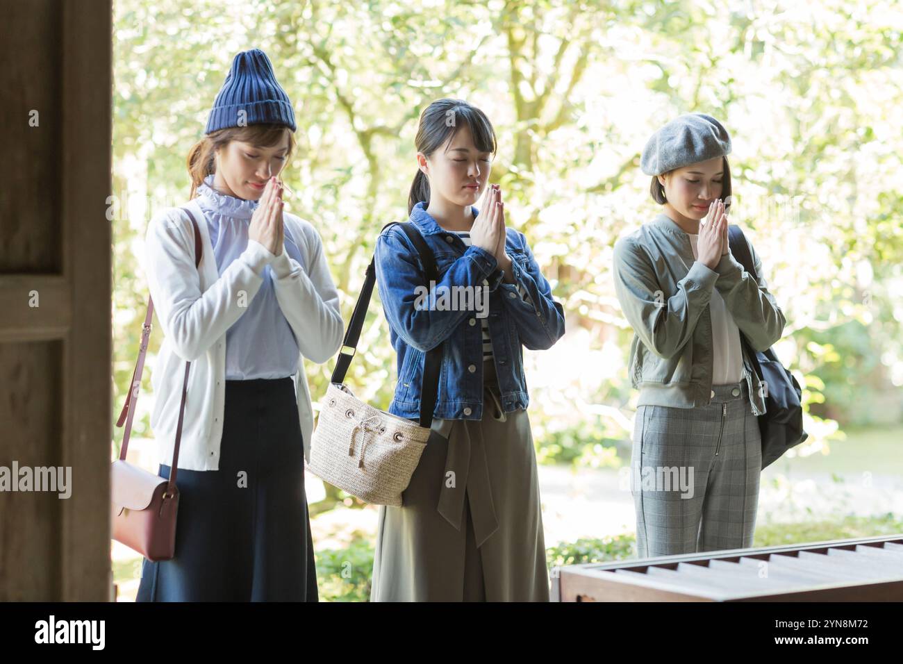 Three women praying at a temple Stock Photo - Alamy