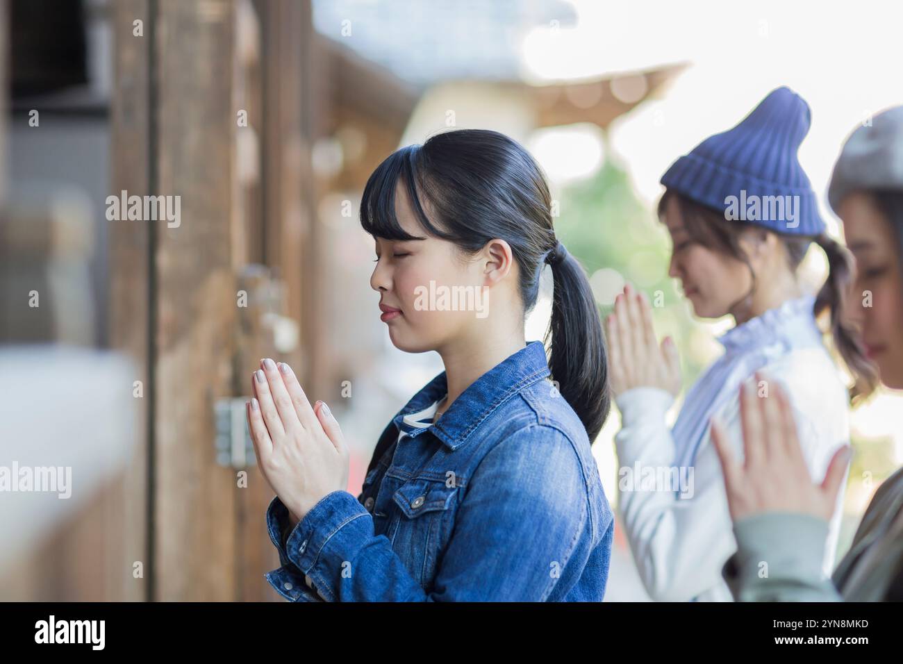 Three women praying at a temple Stock Photo - Alamy