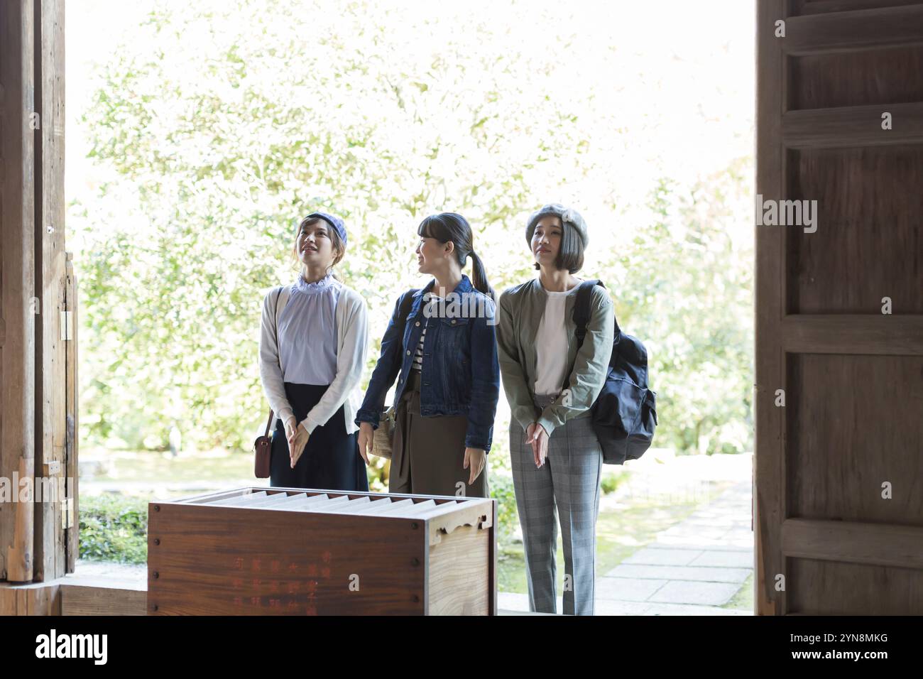 Three women praying at a temple Stock Photo - Alamy