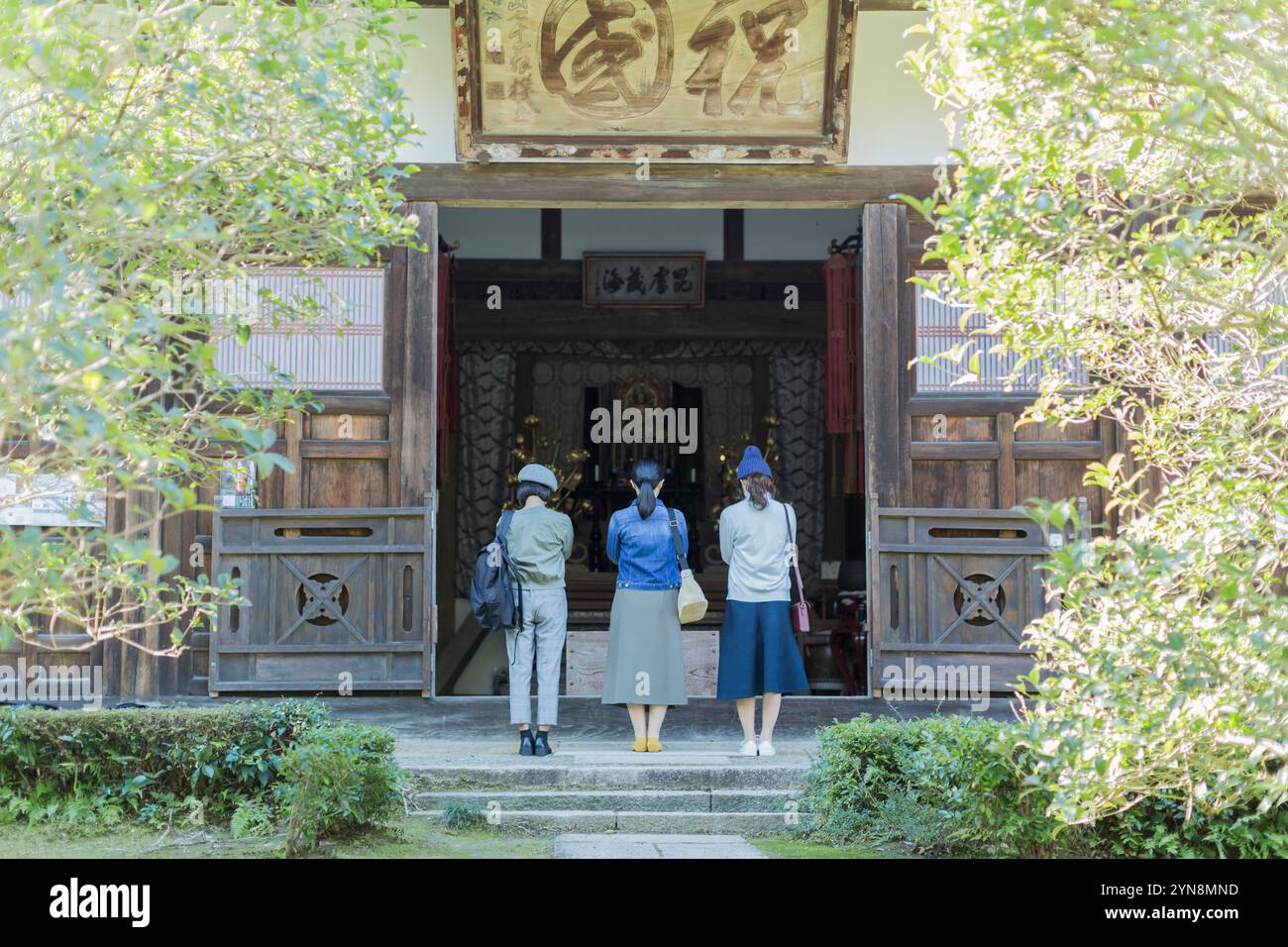 Three women praying at a temple Stock Photo - Alamy
