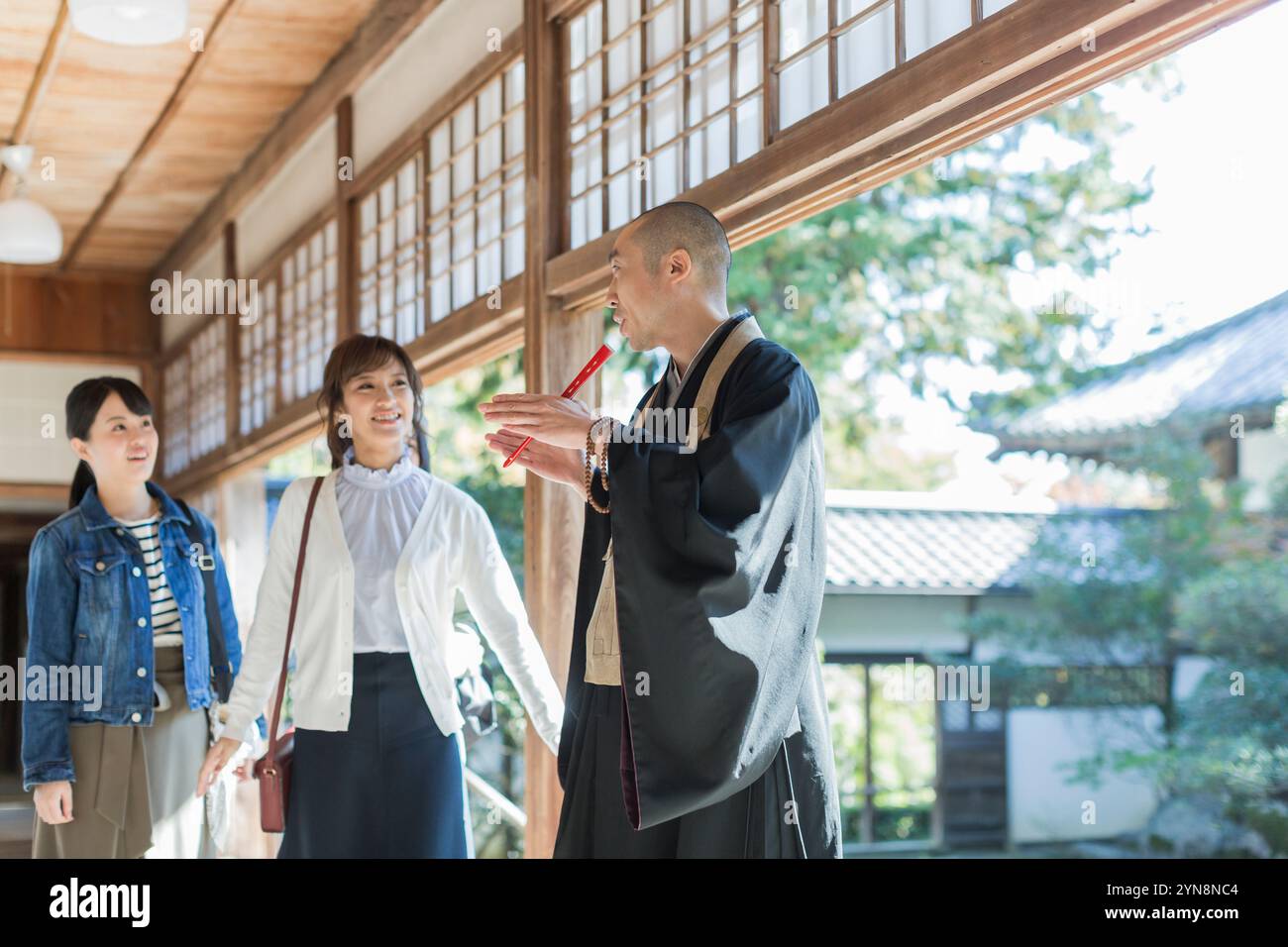 A priest and three women showing around a temple Stock Photo - Alamy
