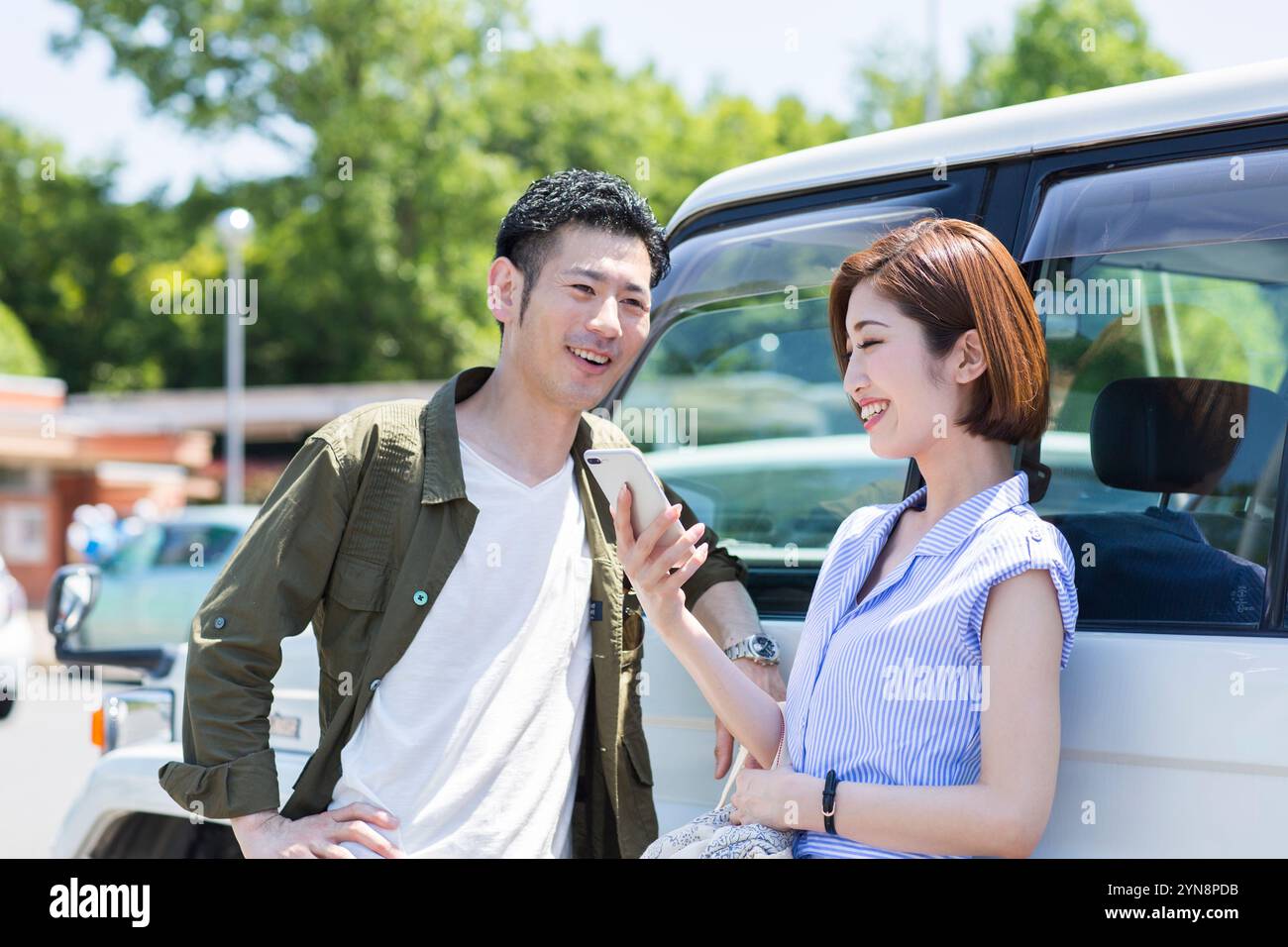 Couple in their 20s and 30s using a mobile phone next to a car Stock ...