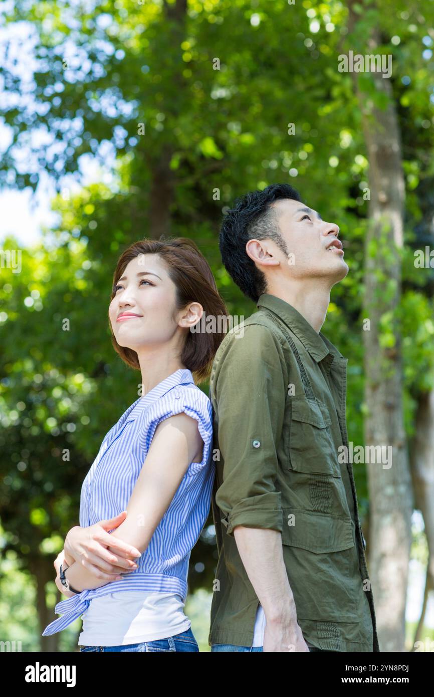 Couple in their 20s and 30s back to back in green Stock Photo - Alamy