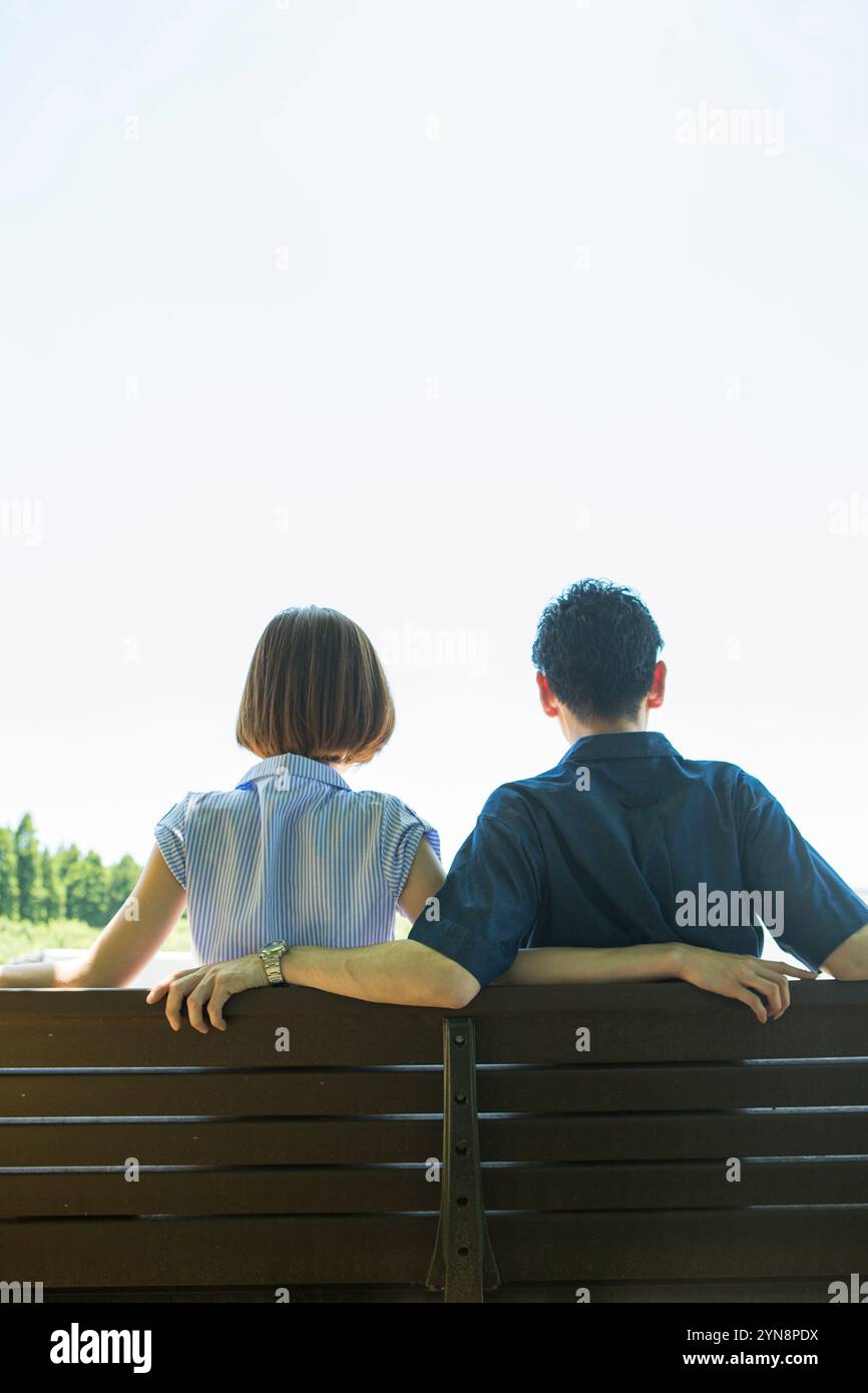 Couple in their 20s and 30s sitting on a bench, back view Stock Photo ...