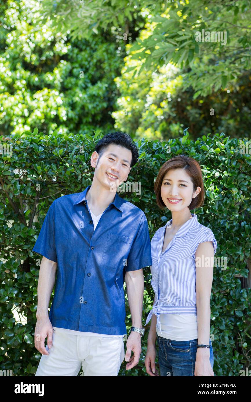Couple in their 20s and 30s smiling in front of green Stock Photo - Alamy