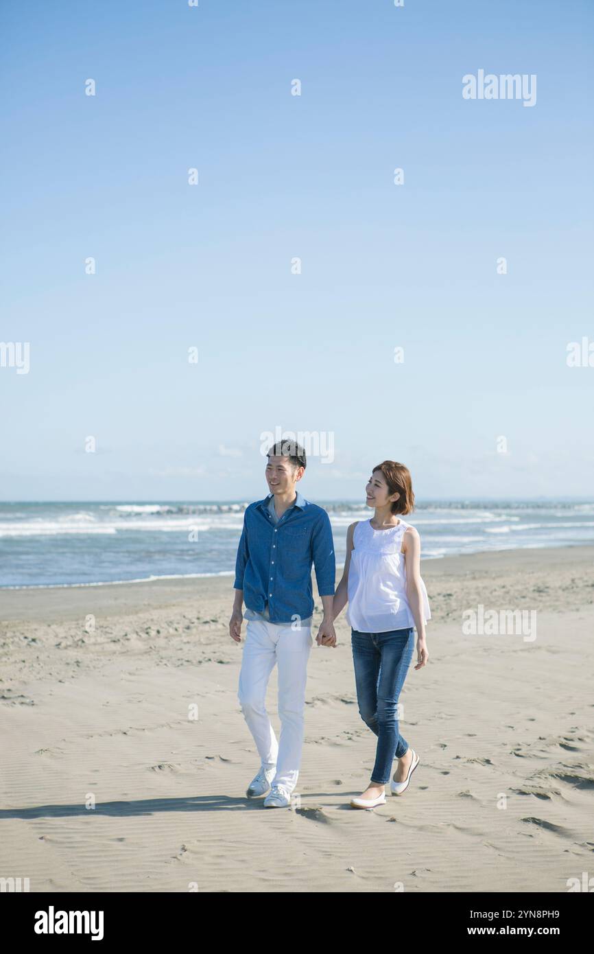Couple in their 20s and 30s walking on sandy beach Stock Photo - Alamy