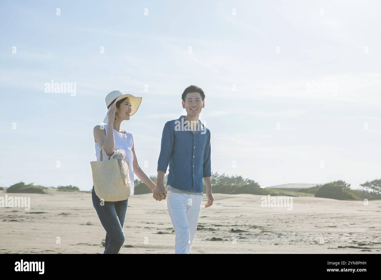 Couple in their 20s and 30s walking on sandy beach Stock Photo - Alamy
