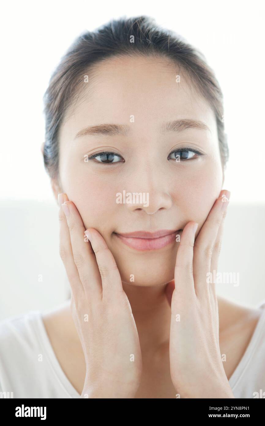 Japanese woman in her 20s patting her cheek Stock Photo - Alamy