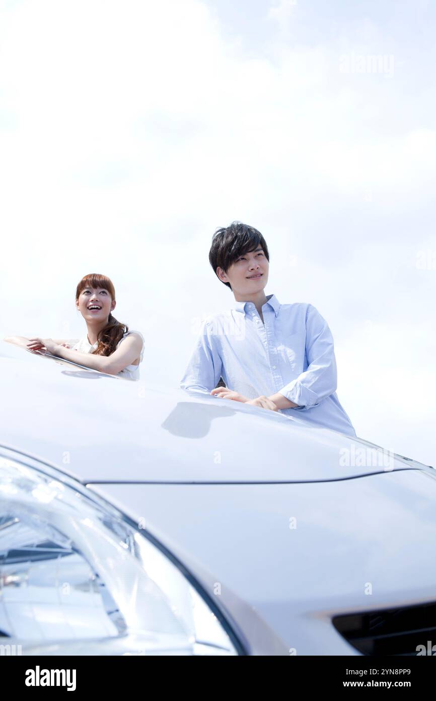 Couple in their 20s standing on side of car Stock Photo - Alamy