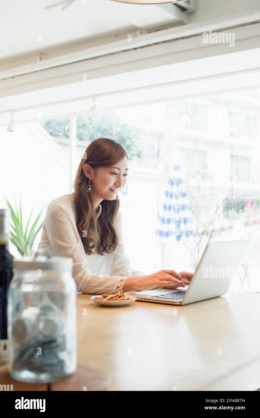 Woman in her 20s operating a computer in a café Stock Photo - Alamy