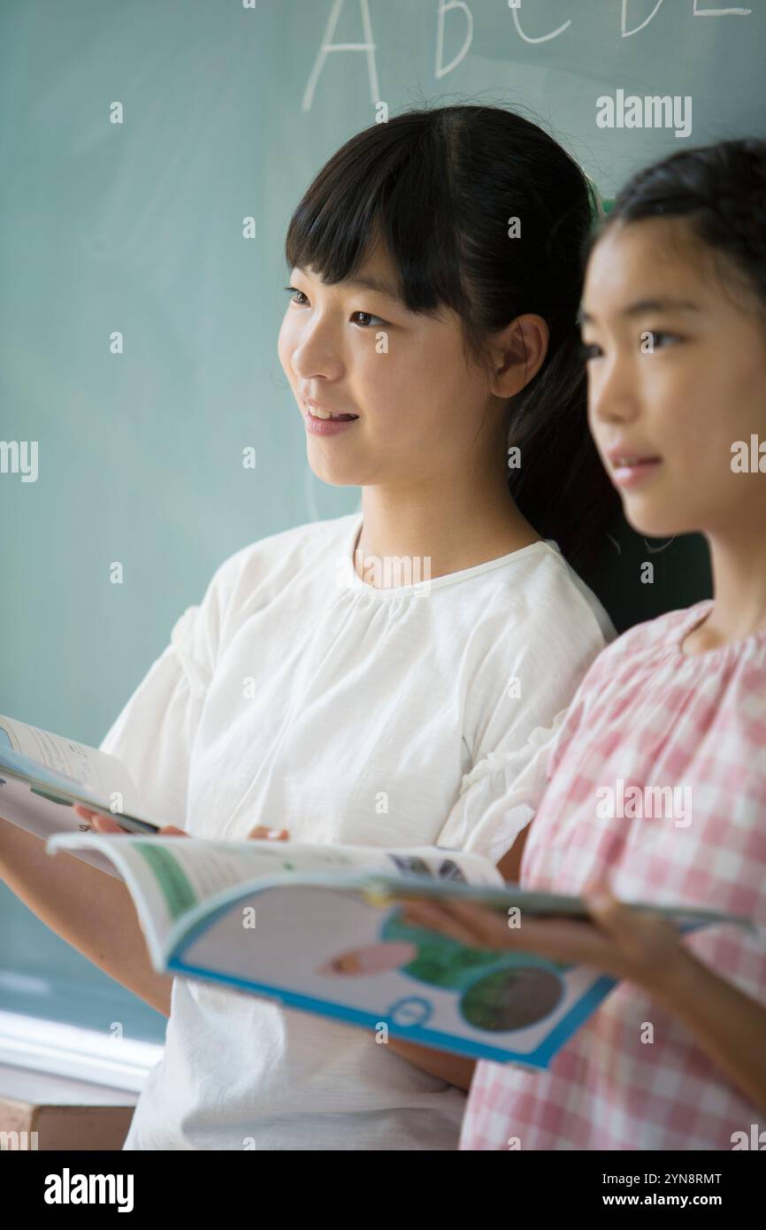 Two girls reading a textbook Stock Photo - Alamy