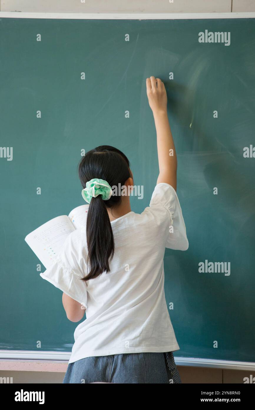 Girl writing on the blackboard Stock Photo - Alamy