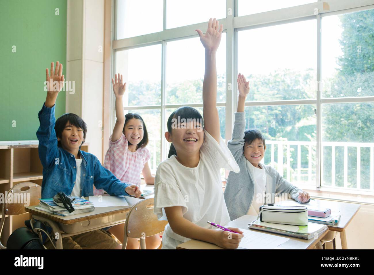 Primary schools children raising their hands Stock Photo - Alamy