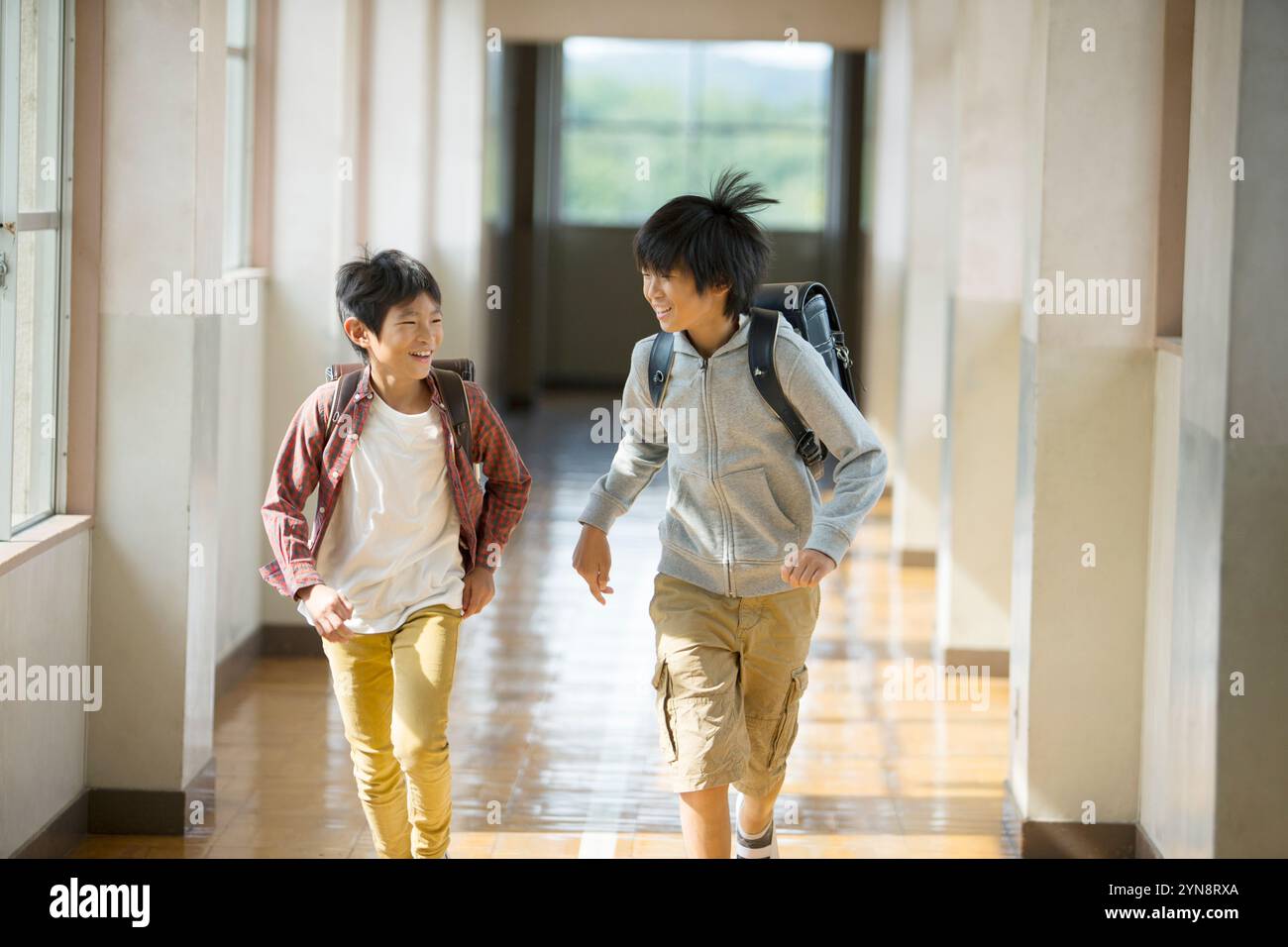 Two smiling primary school boys running down corridor Stock Photo - Alamy