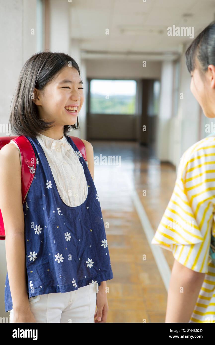 Two primary schools girls talking in corridor Stock Photo - Alamy