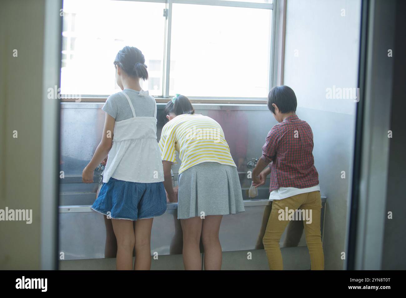 Back view of primary schools boys and girls washing their hands at a ...