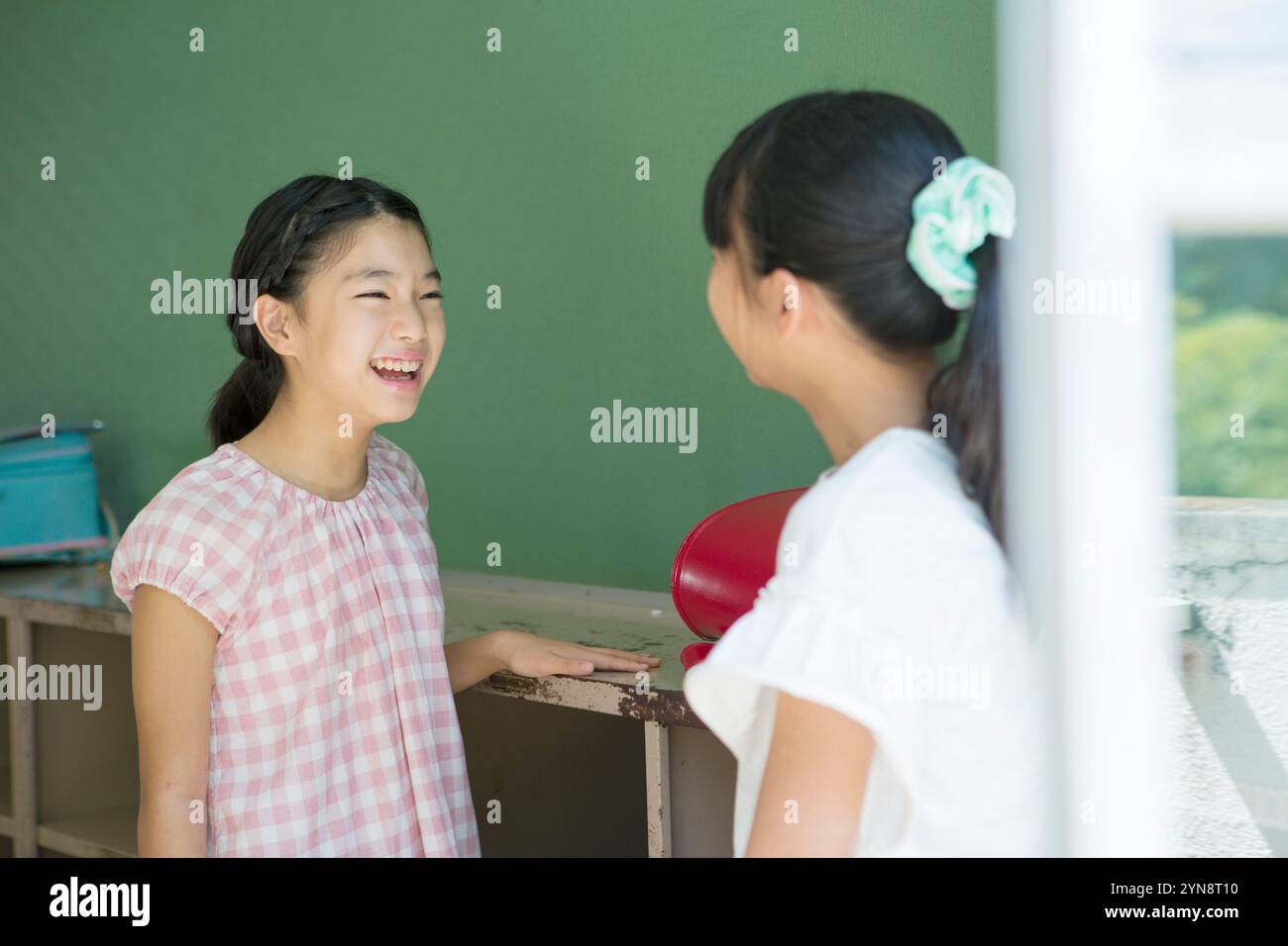 Two smiling girls talking in the classroom Stock Photo - Alamy