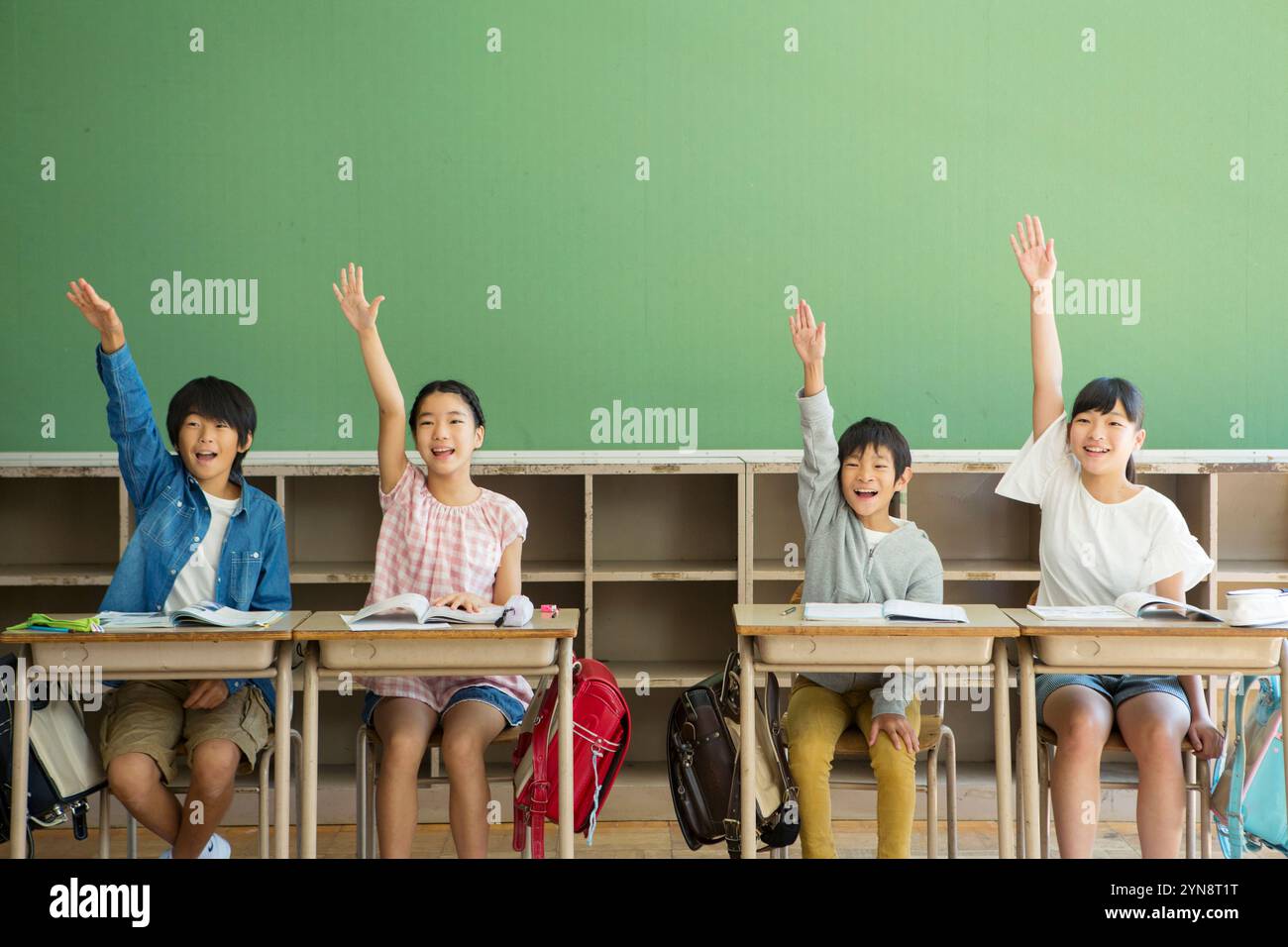 Primary schools children raising their hands Stock Photo - Alamy