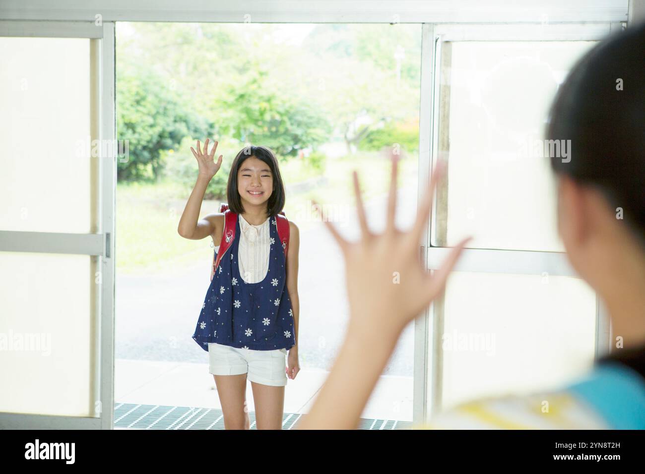 Two schoolgirls waving Stock Photo - Alamy