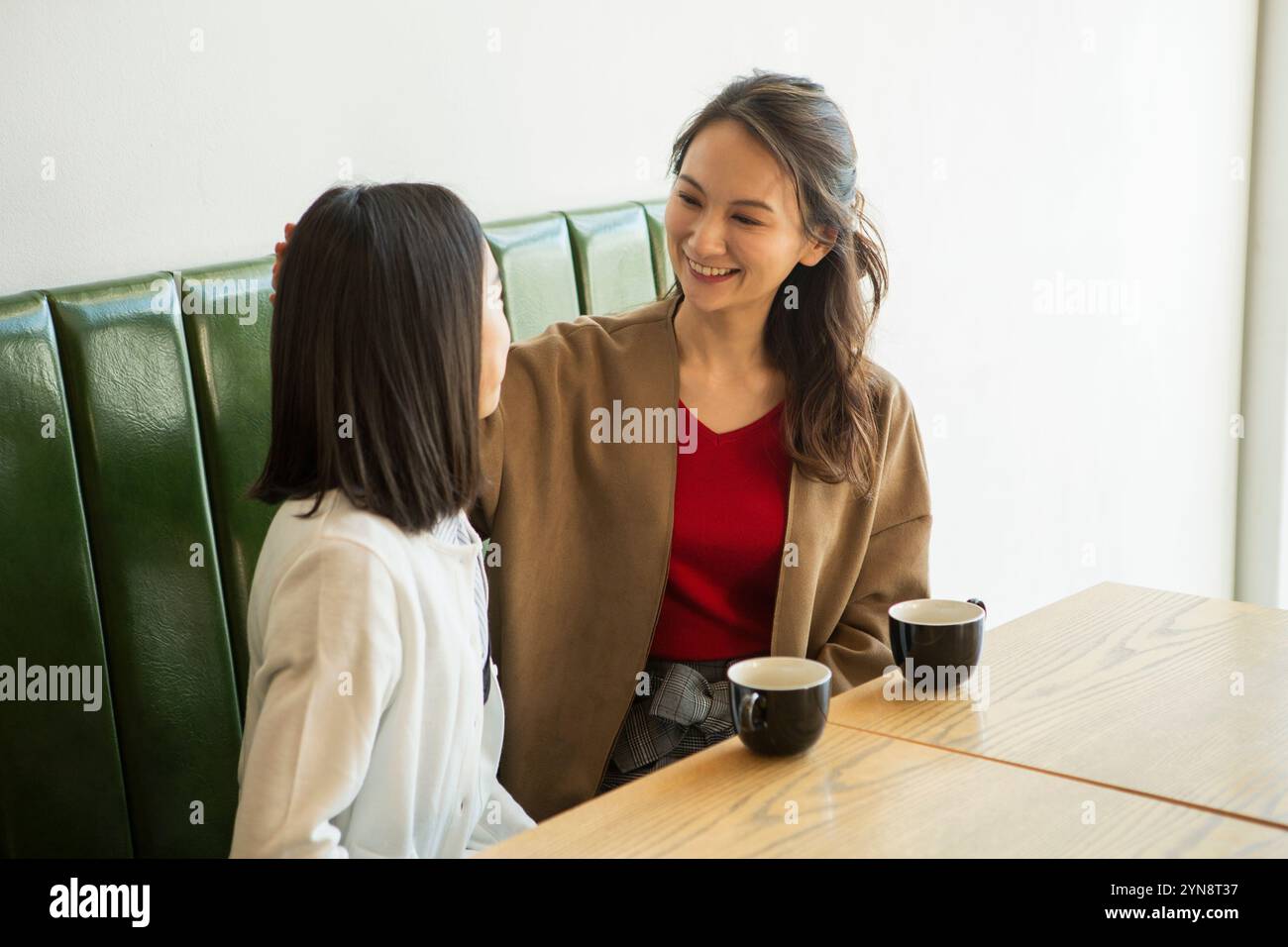 Mother patting daughter's head at café Stock Photo - Alamy