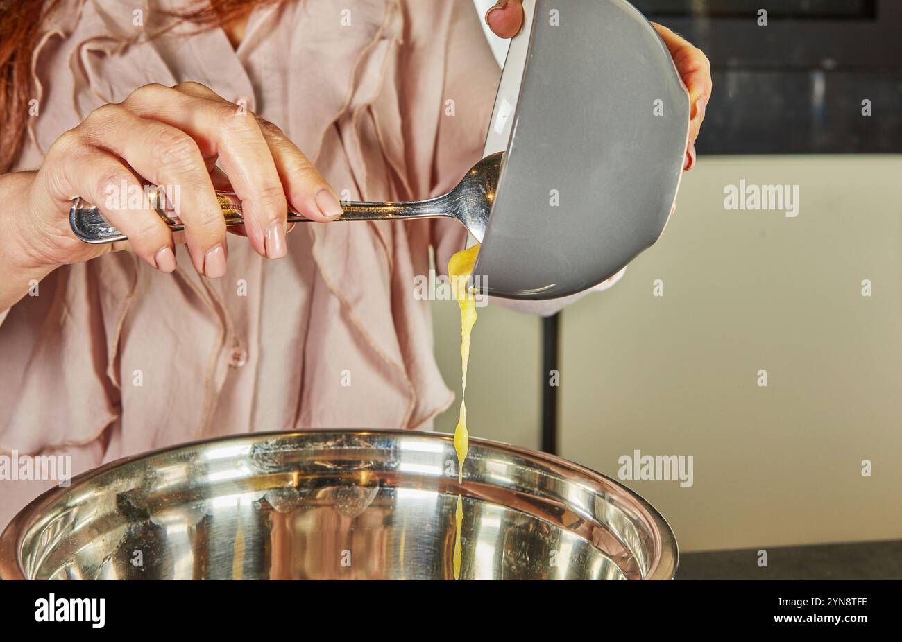 A person crumbles cookies into a mixing bowl, creating fine crumbs for ...