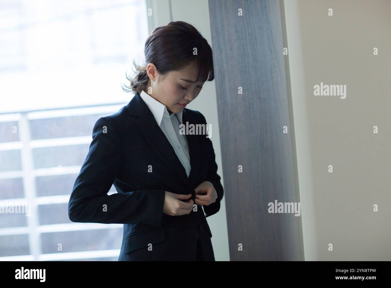 Woman in her 20s buttoning up her suit Stock Photo - Alamy