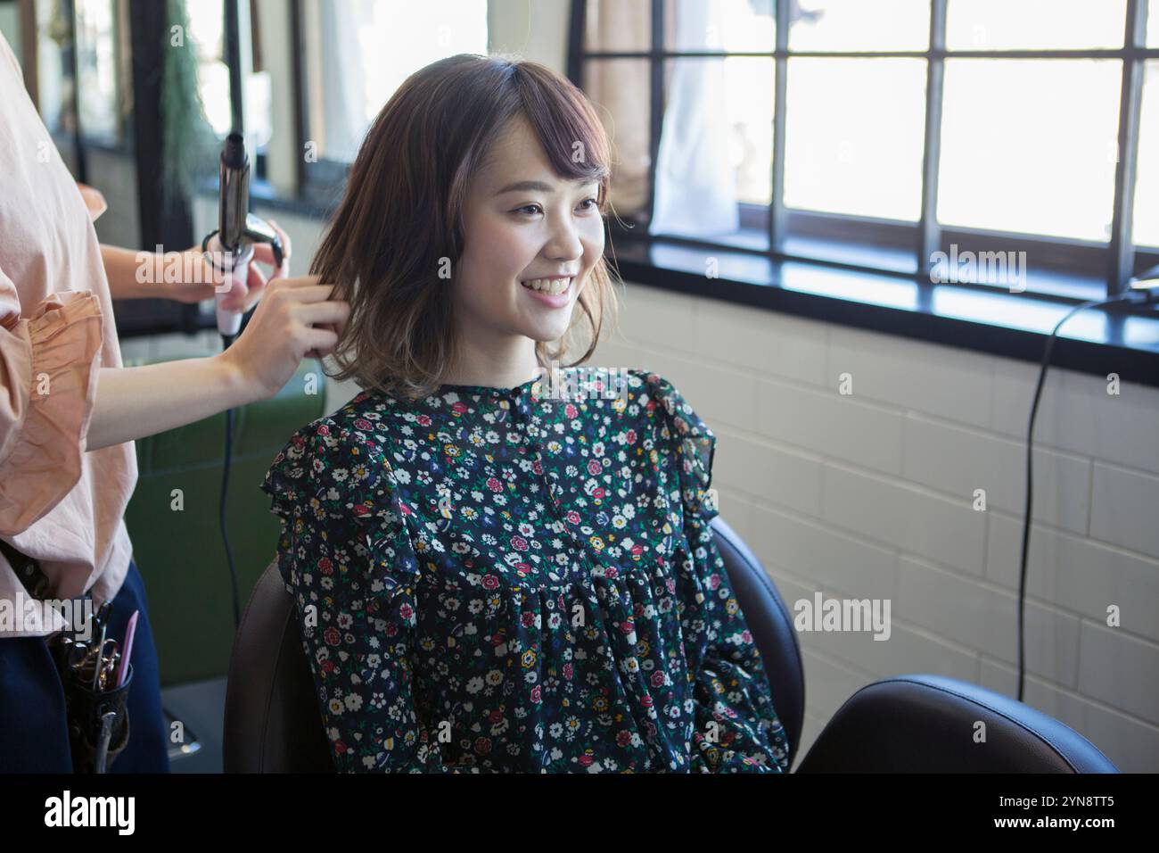 Smiling 20s woman getting a styling at a beauty salon Stock Photo - Alamy