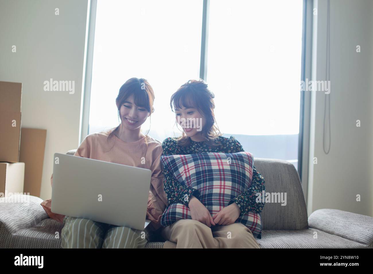 Two smiling women in their 20s looking at a computer Stock Photo - Alamy